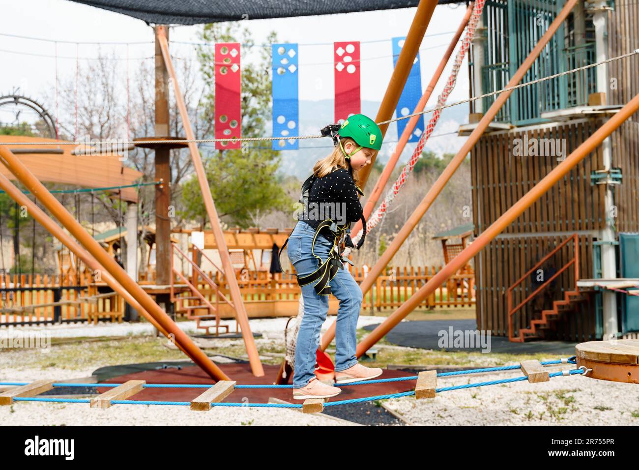 Teenage teen girl in climbing harness equipment, green sports safety ...