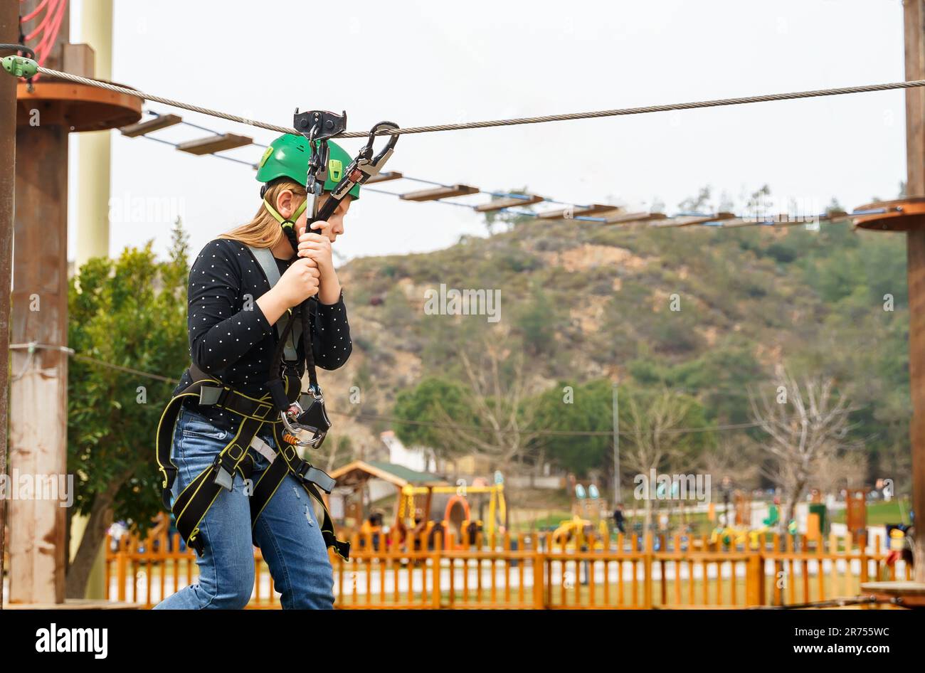 Teenage teen girl in climbing harness equipment, green sports safety ...