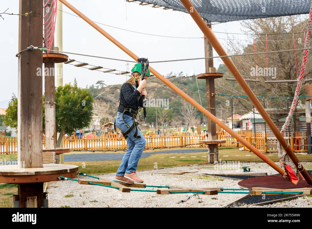 Teenage teen girl in climbing harness equipment, green sports safety ...