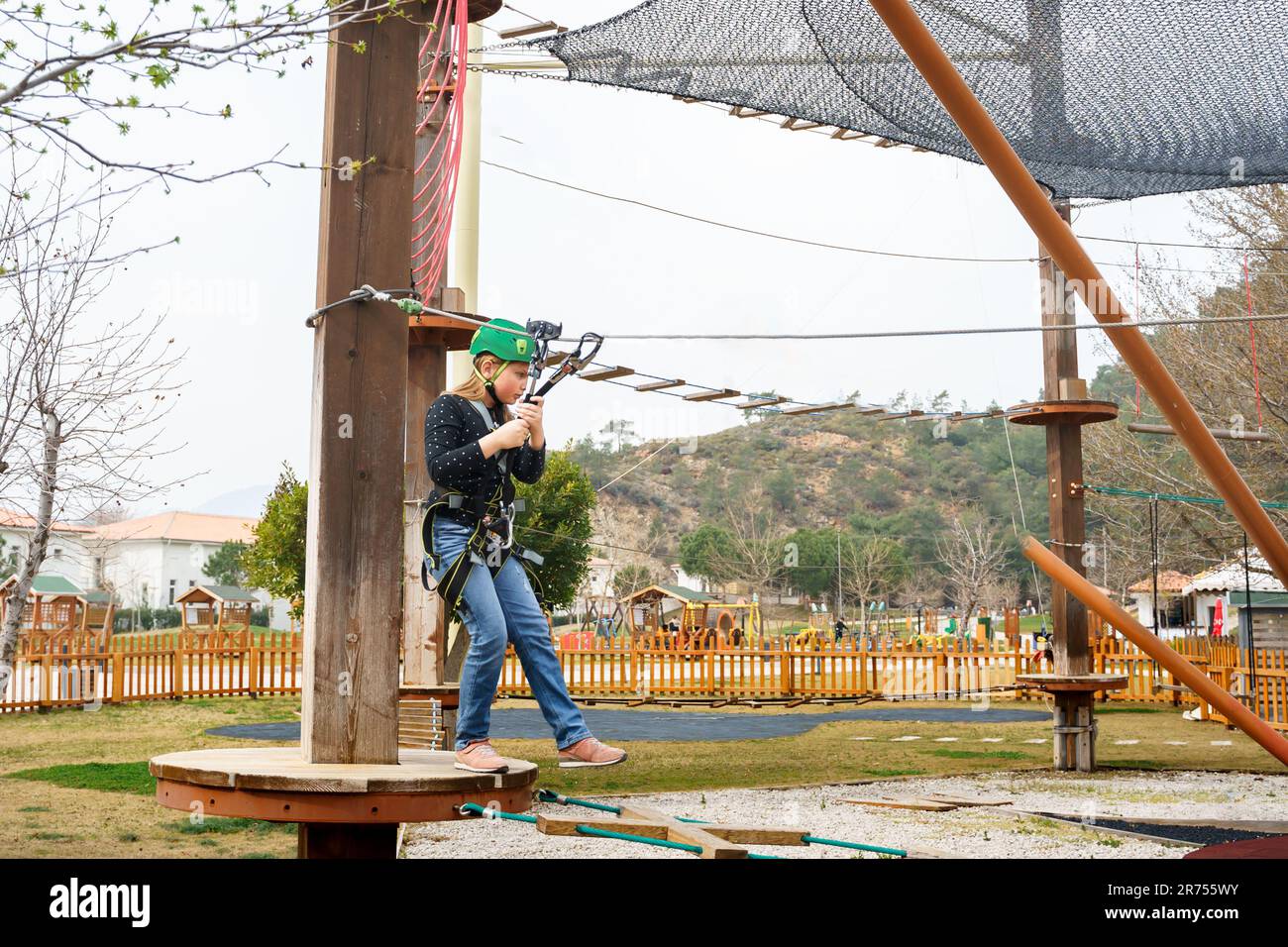 Teenage teen girl in climbing harness equipment, green sports safety ...