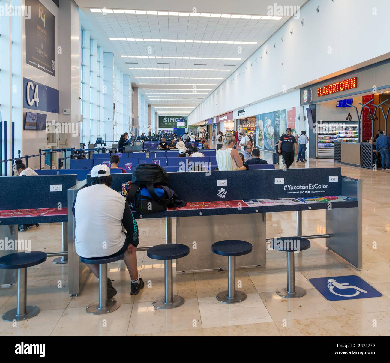 People and shops in departure loungs waiting area inside Merida airport ...