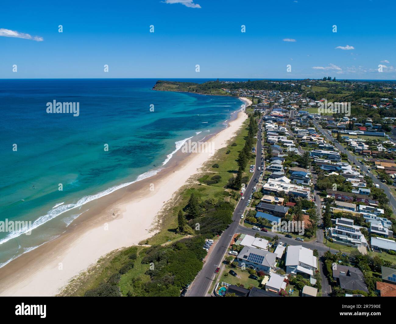 An aerial view of a sandy beach and the blue ocean with houses along ...