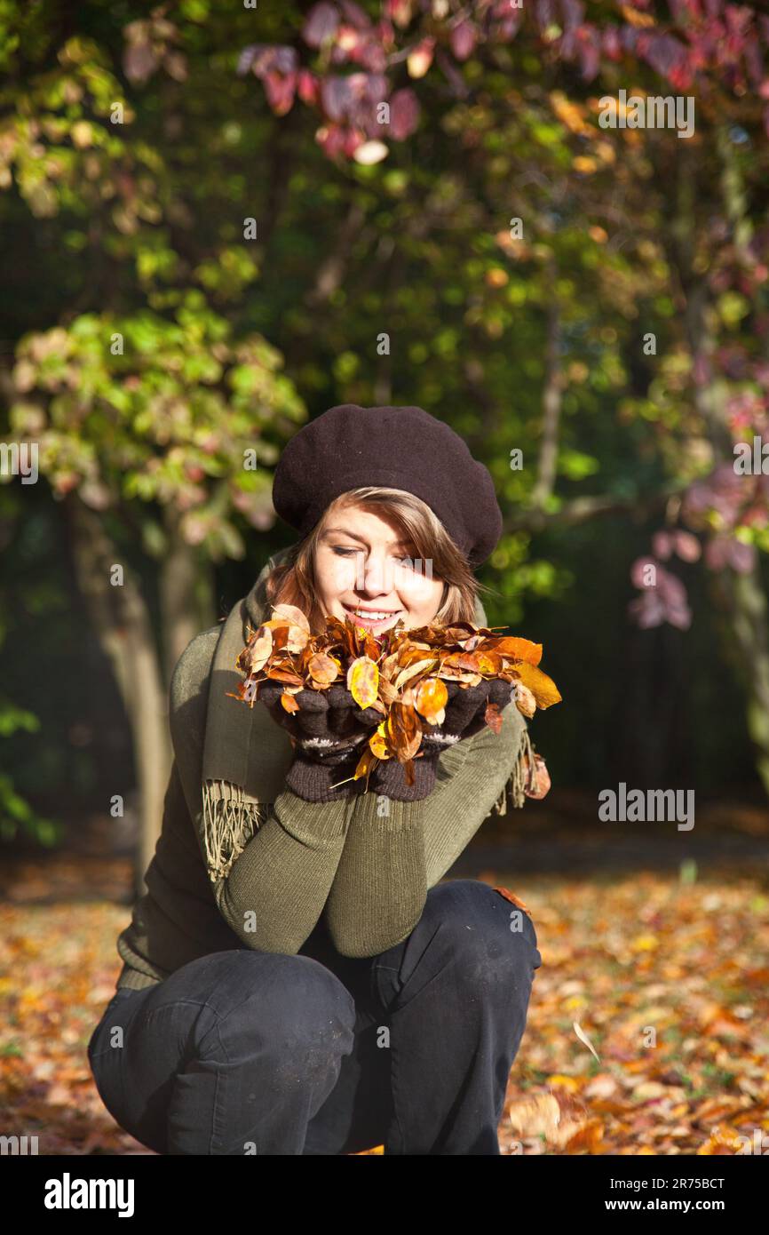 crouching woman enjoying autumn leaves, front view Stock Photo - Alamy