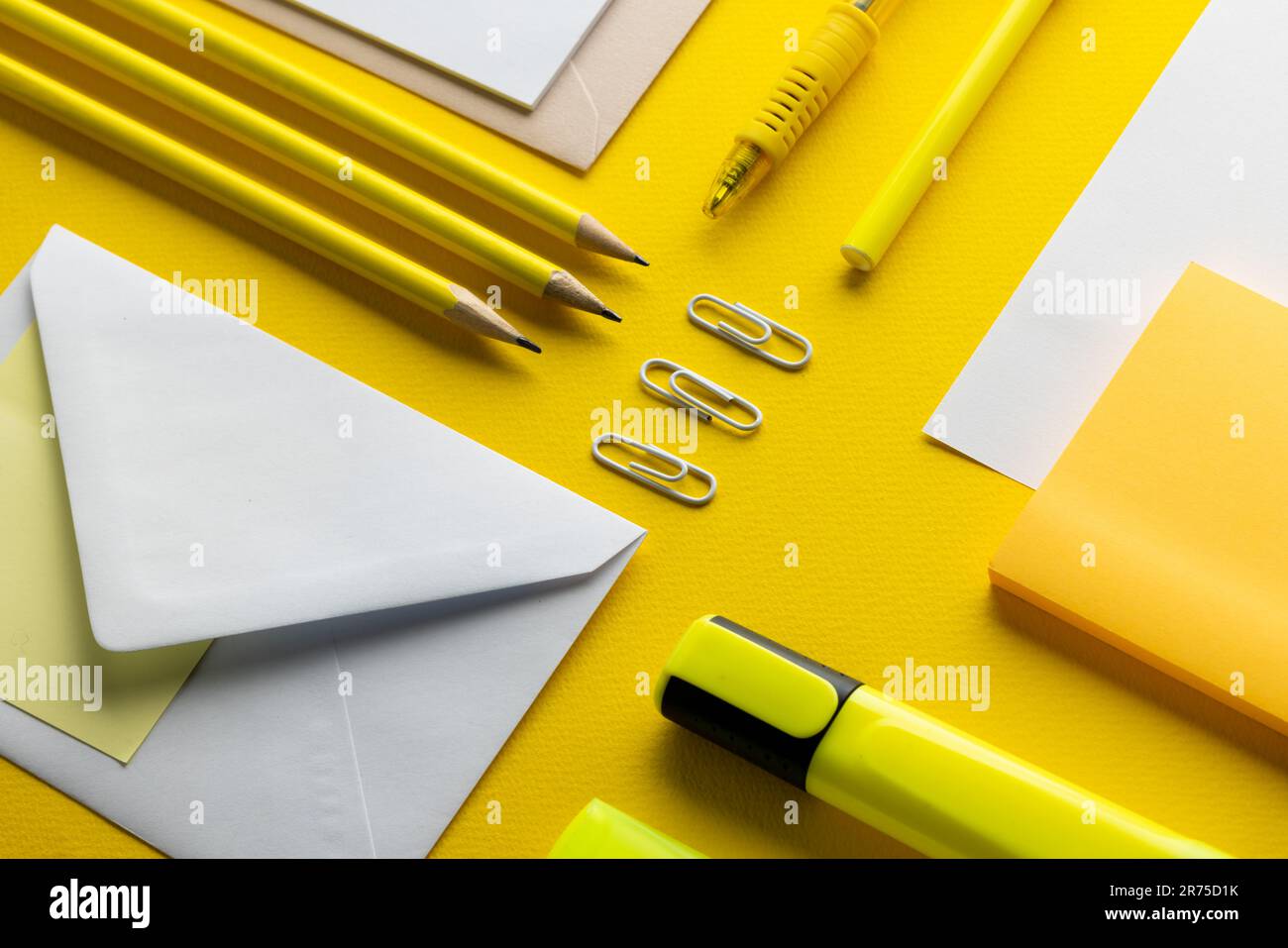 Flat lay of yellow pencils, pen and highlighter and white paper with ...