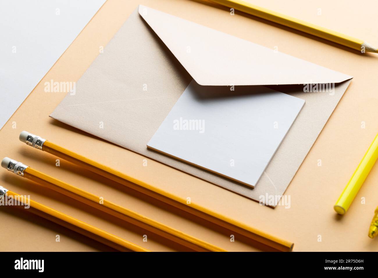 Flat lay of yellow pencils and marker, envelope and white paper with ...