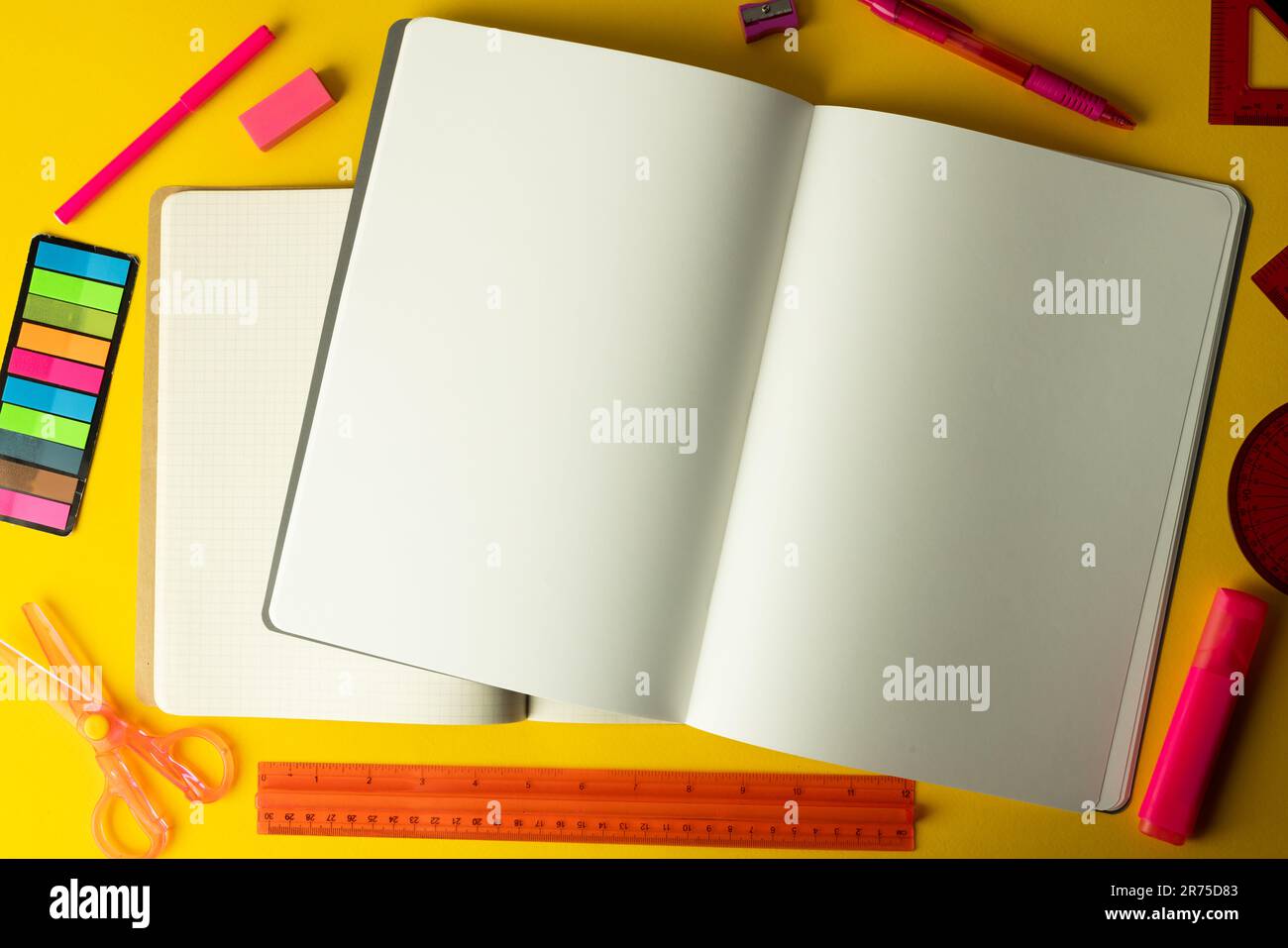 Flat lay of notebook with copy space and writing materials on yellow ...