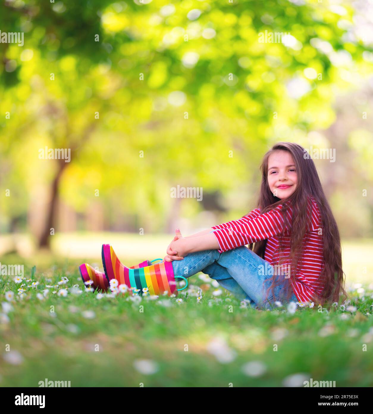 Cute toddler girl in rain rubber boots playing outside in the green ...