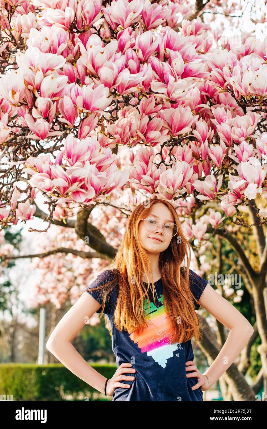 Spring portrait of adorable red-haired preteen kid girl with magnolia ...