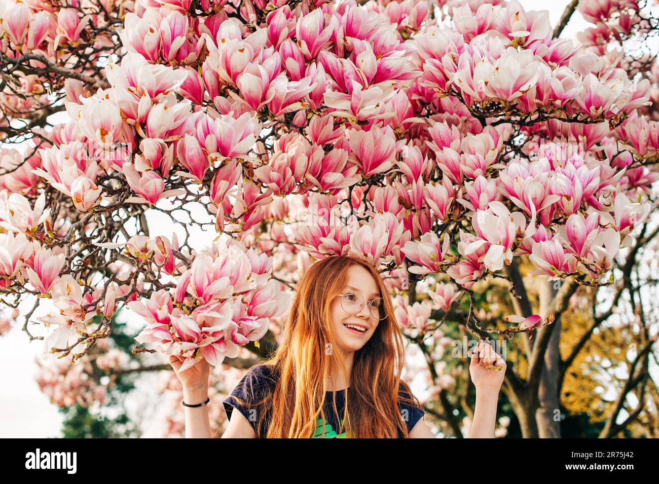 Spring portrait of adorable red-haired preteen kid girl with magnolia ...