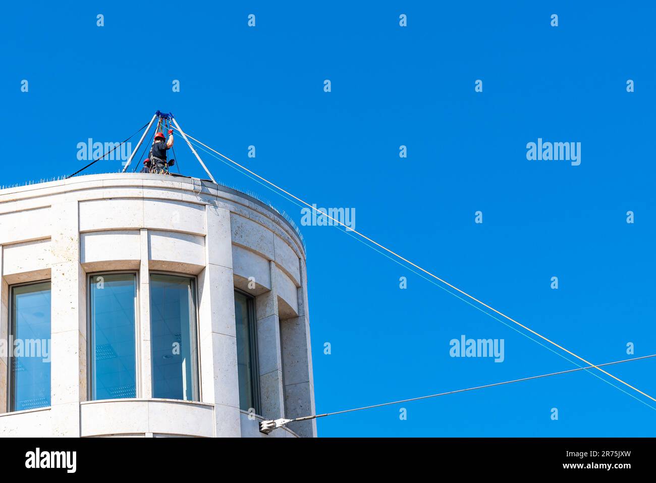 Construction workers pull a rope on the roof of a building. Against the ...