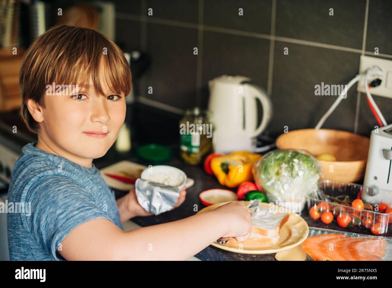 Cute little boy making salmon sandwich with fresh ingredients ...