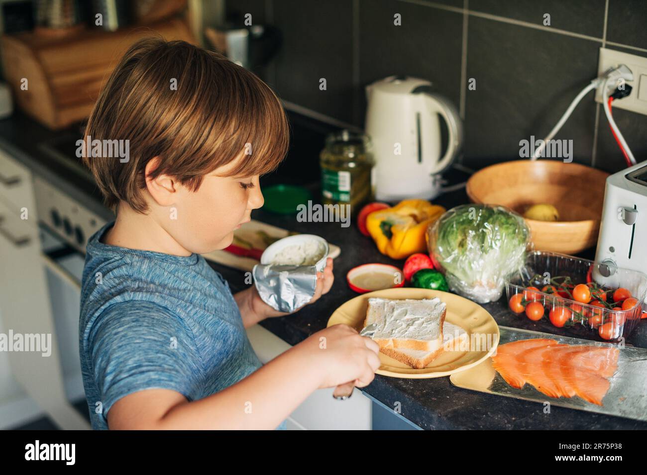 Cute little boy making salmon sandwich with fresh ingredients ...