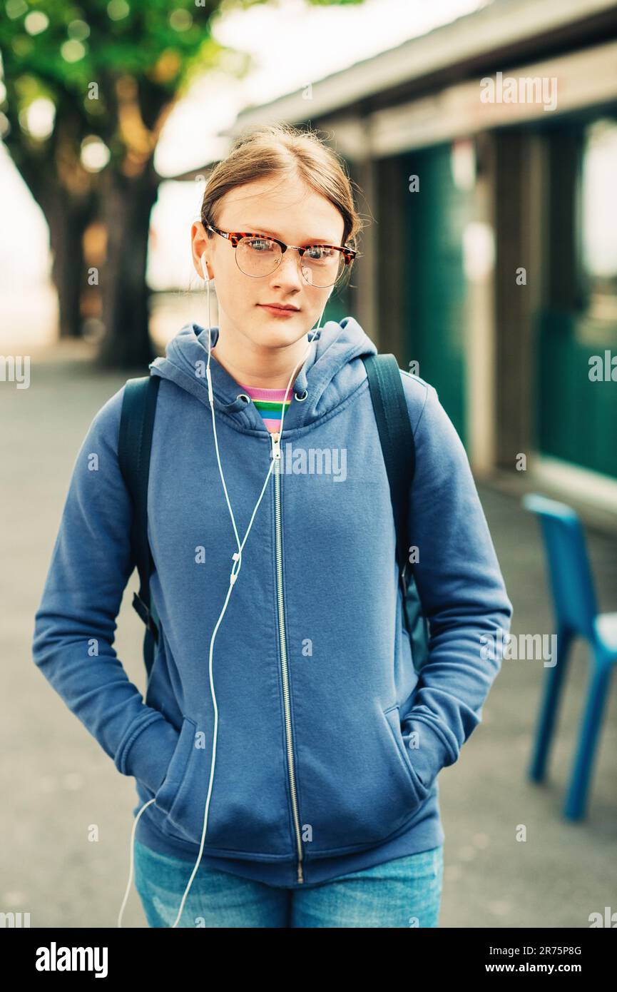 Outdoor portrait of young preteen girl wearing backpack and eyeglasses ...