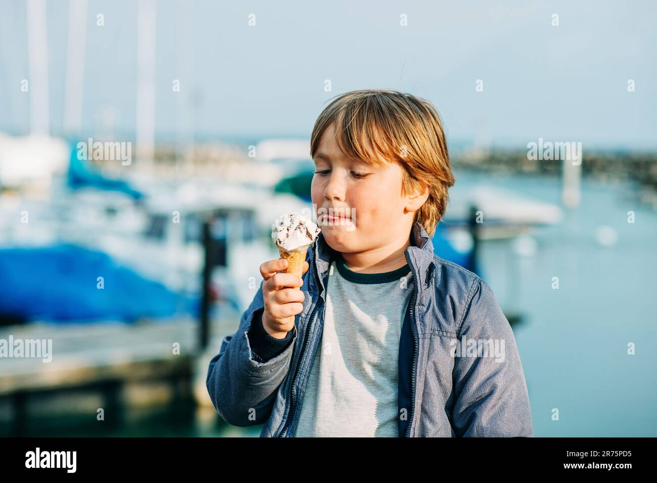 Cute little boy eating ice cream by the lake on a cold day Stock Photo ...