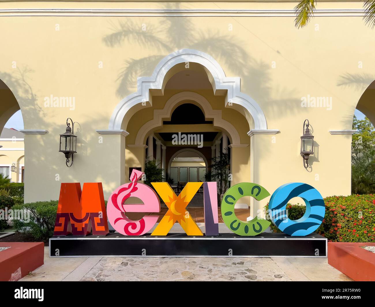 A colorful Mexico sign in an outdoor courtyard with an arched doorway ...