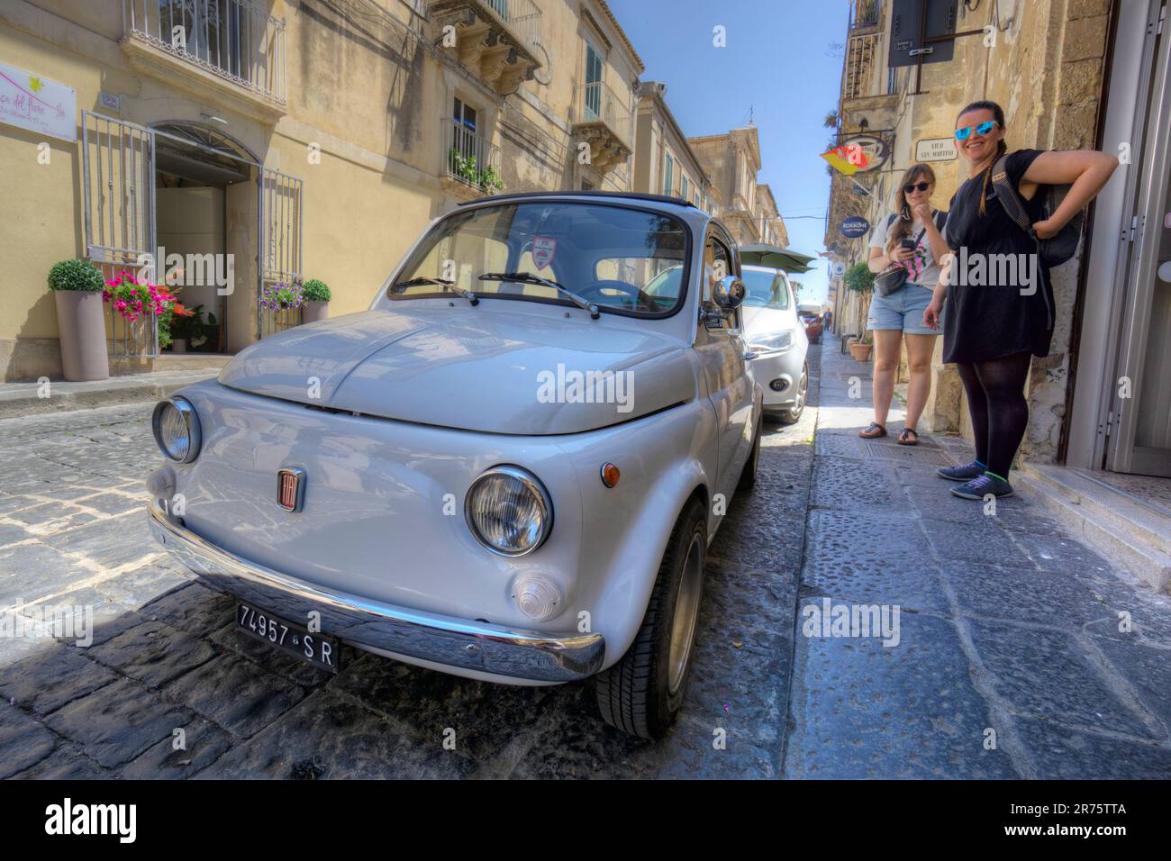 Fiat 500 bubble car parked in narrow street in rococo town Noto cobbled ...