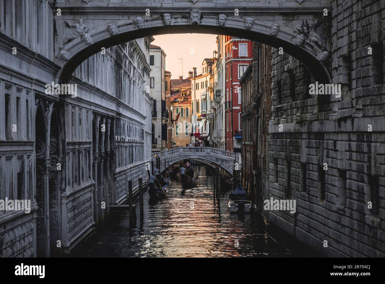 View through an arch over a canal to the last sunlit houses in Venice ...