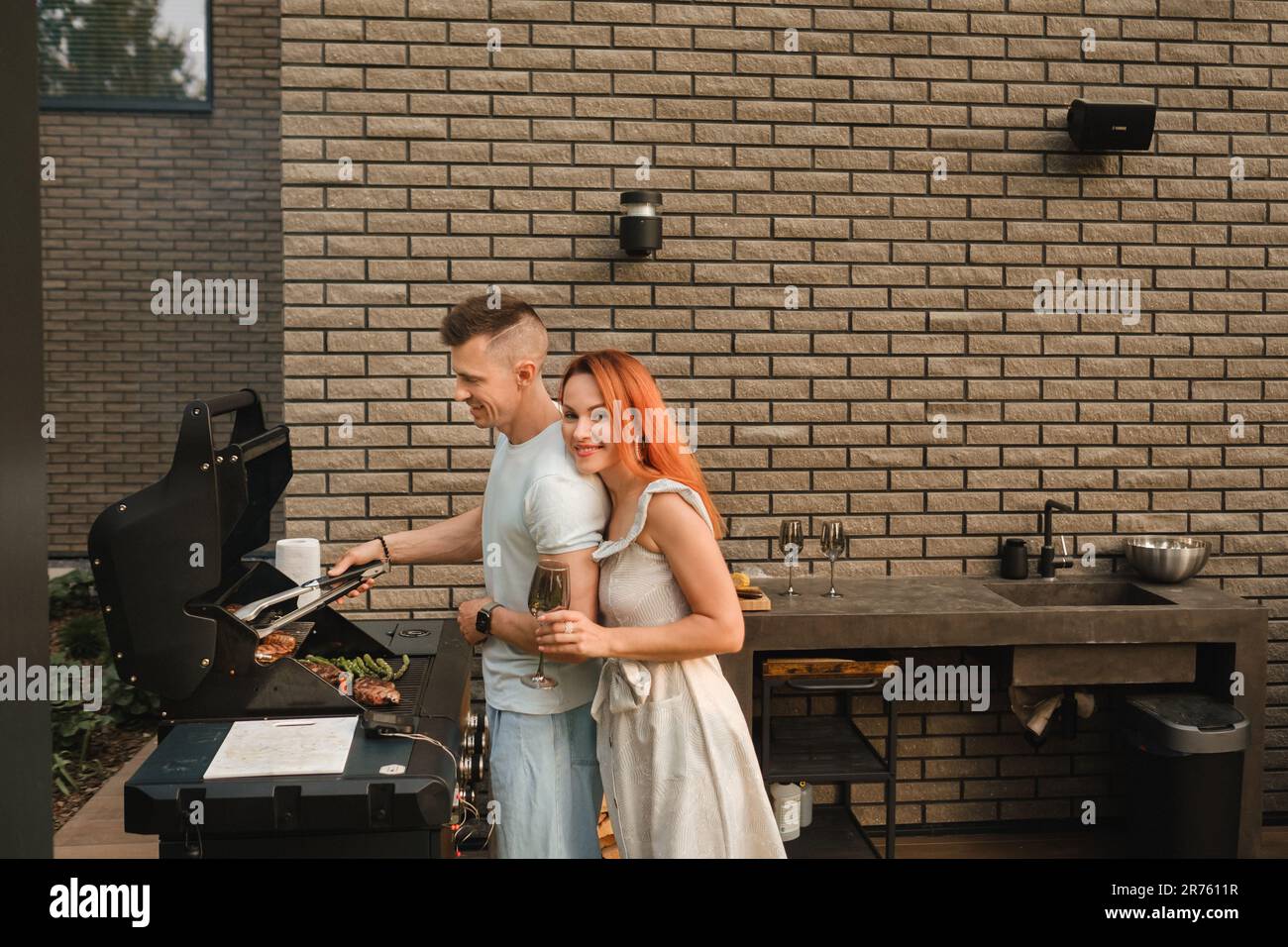 A married couple cooks grilled meat together on their terrace Stock ...