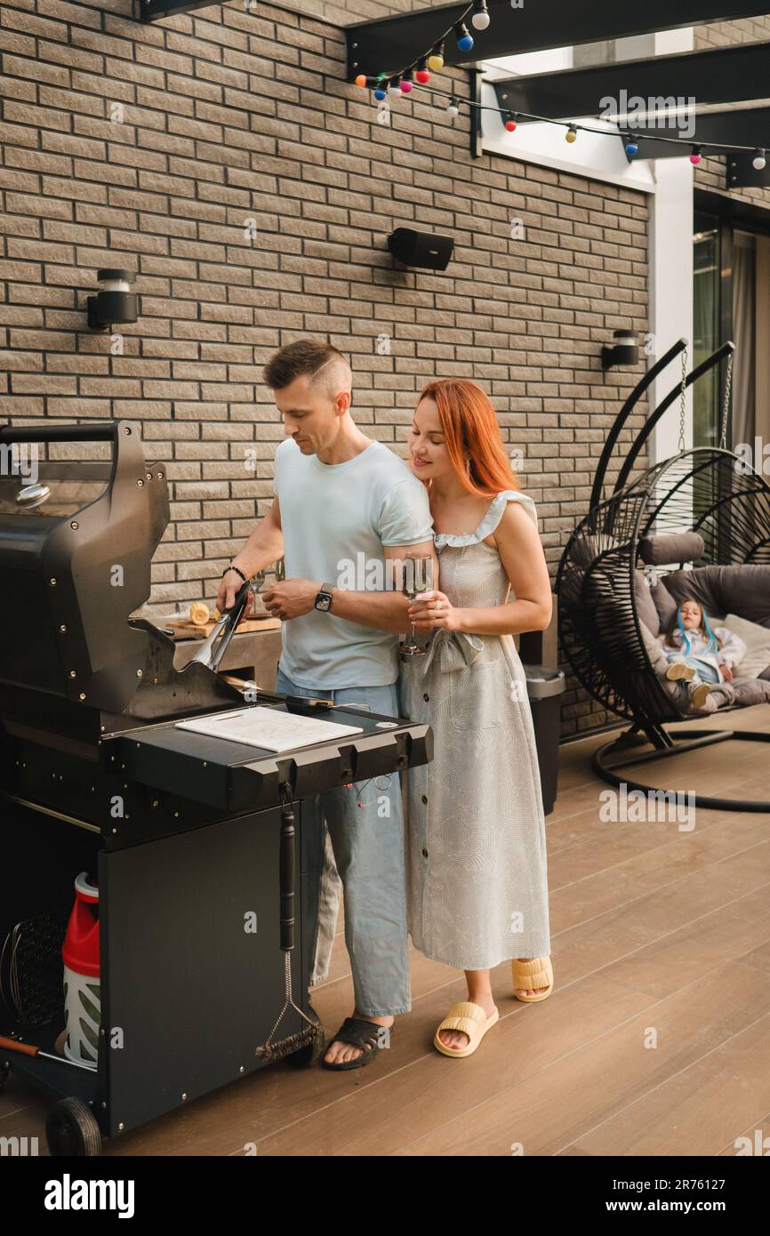 A married couple cooks grilled meat together on their terrace Stock ...
