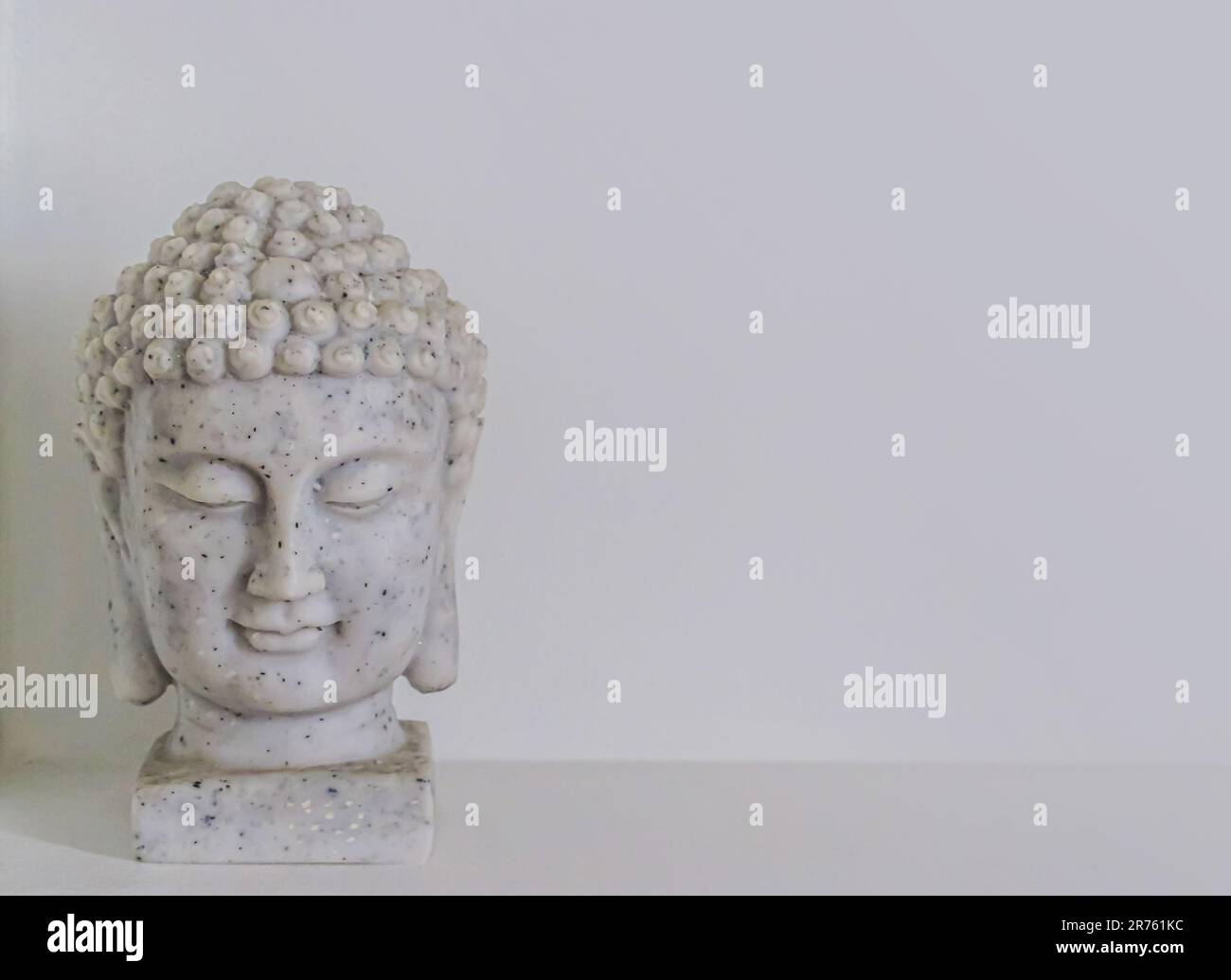 Close-up of Ceramic Statuette of a Buddha head on a grey background ...