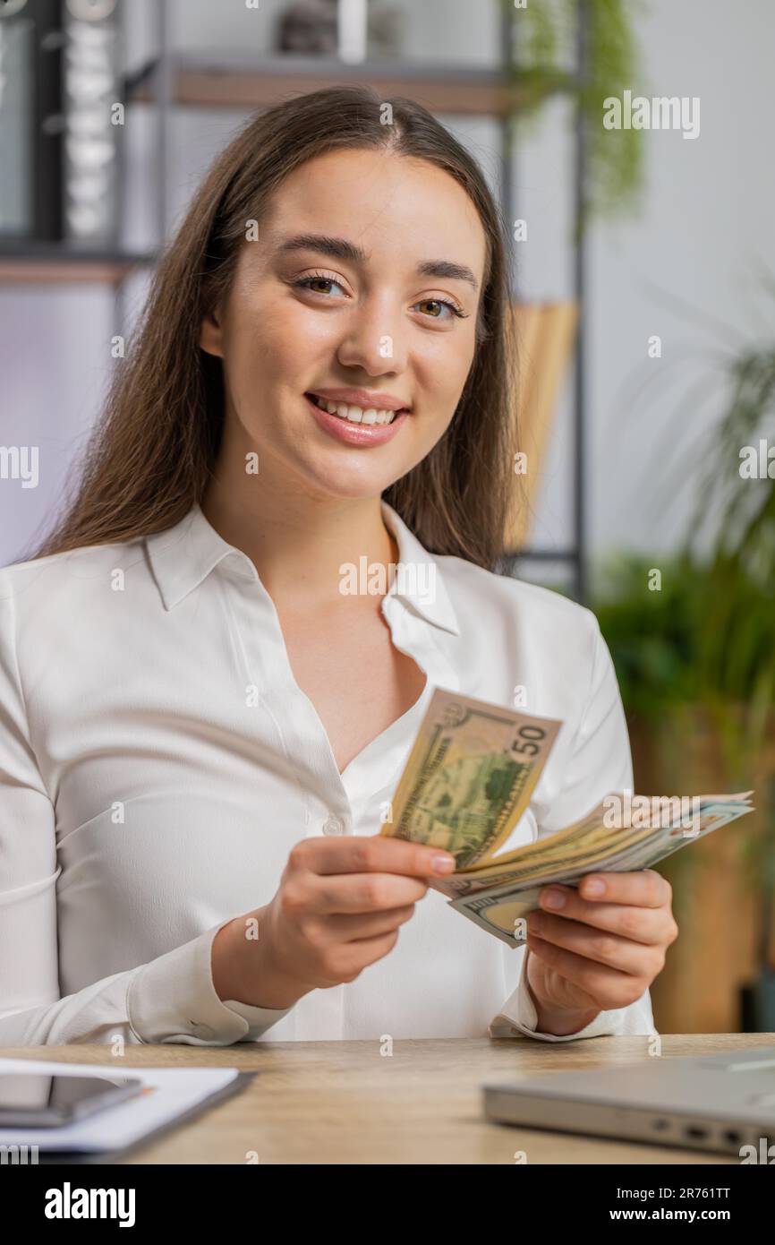 Rich Caucasian business woman working on laptop counting money cash ...
