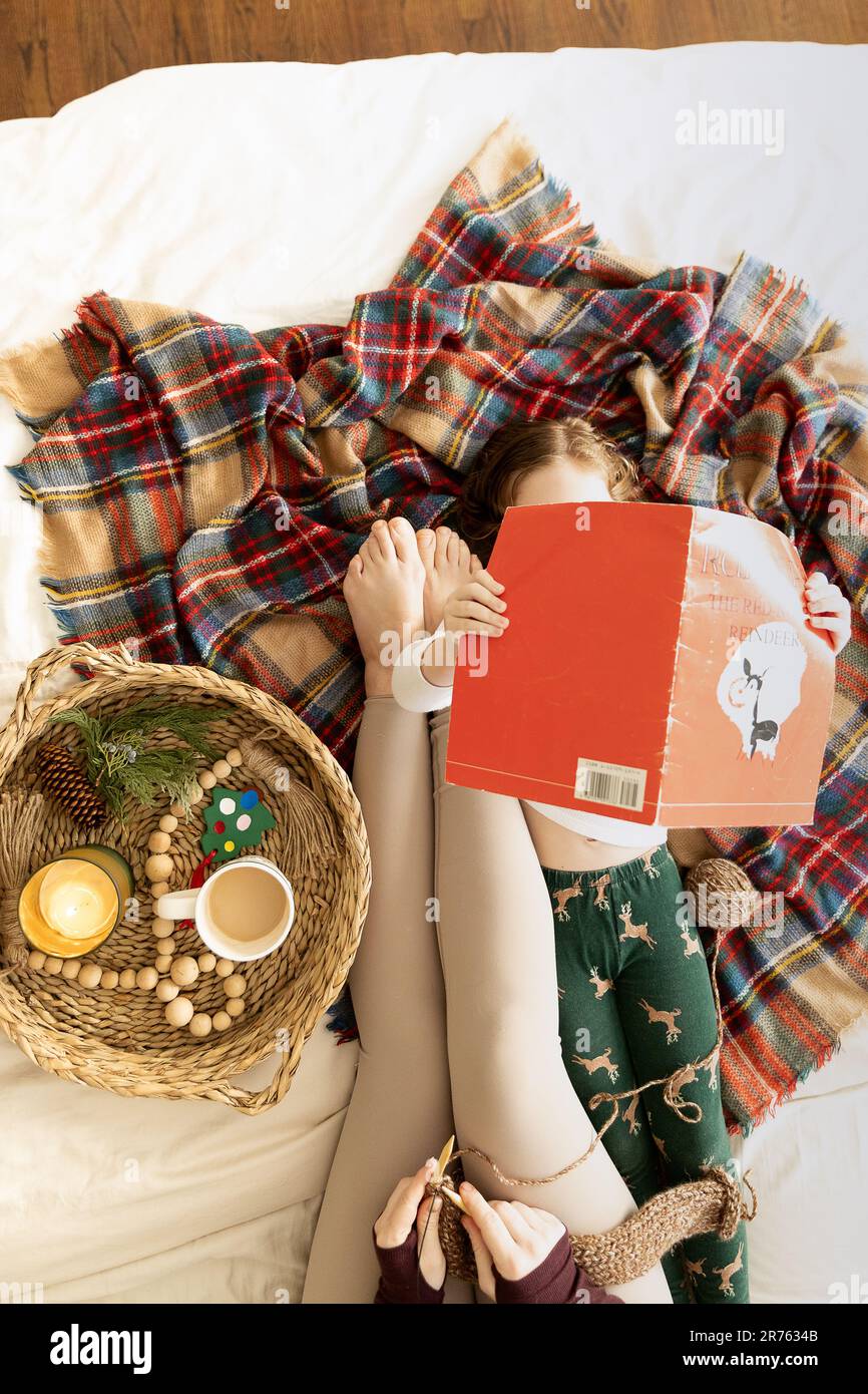 A bird's eye view of a little girl reading a book next to her mother's ...