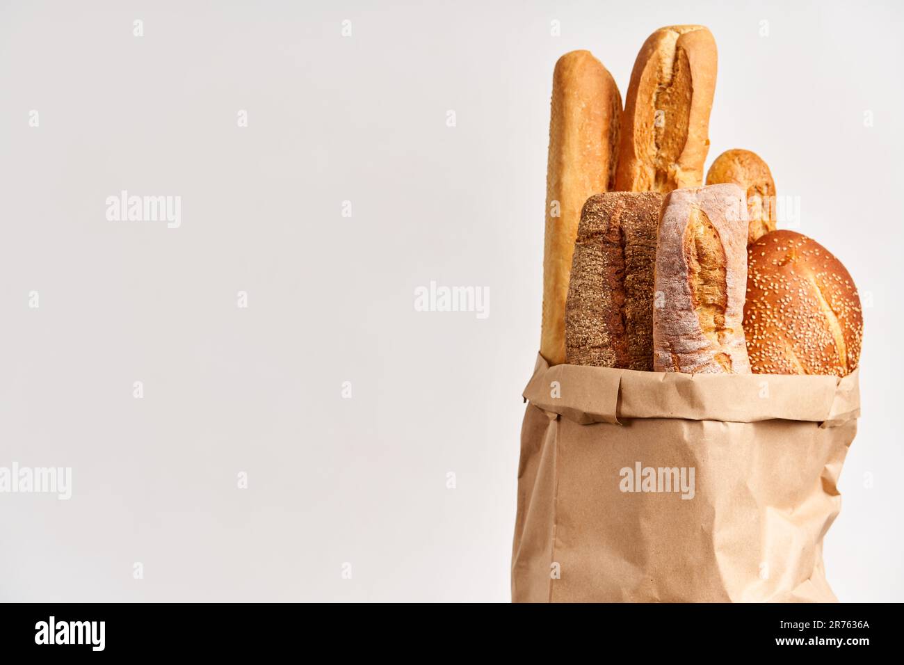 Different types of french bread baguettes in paper bag over white ...