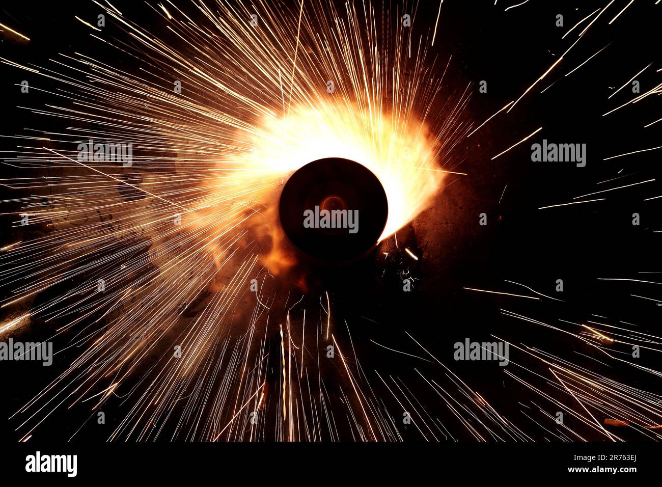 A metal object emitting bright sparks of fireworks in a dark and ...