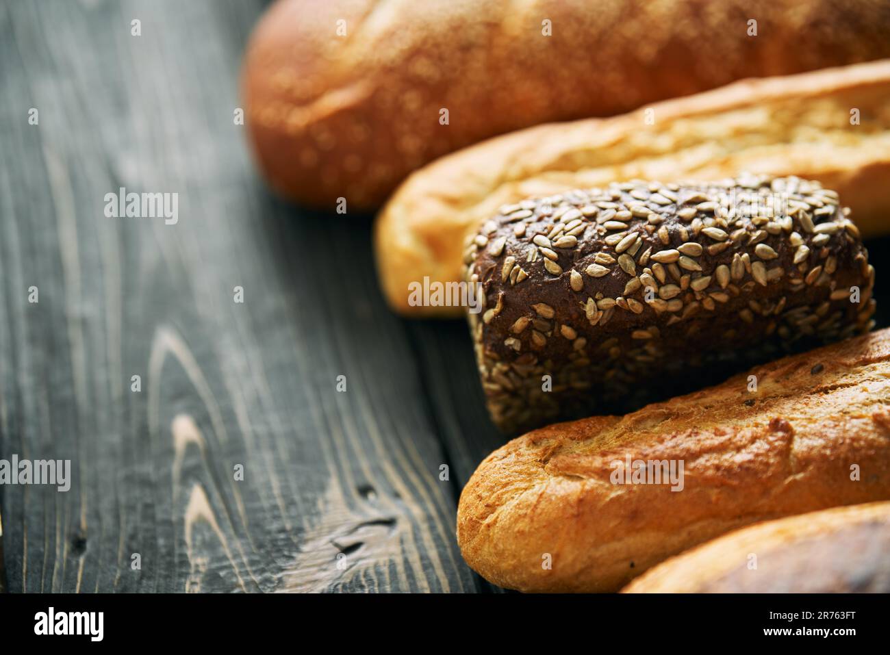 Different types of bread loaves on dark wooden background with copy ...