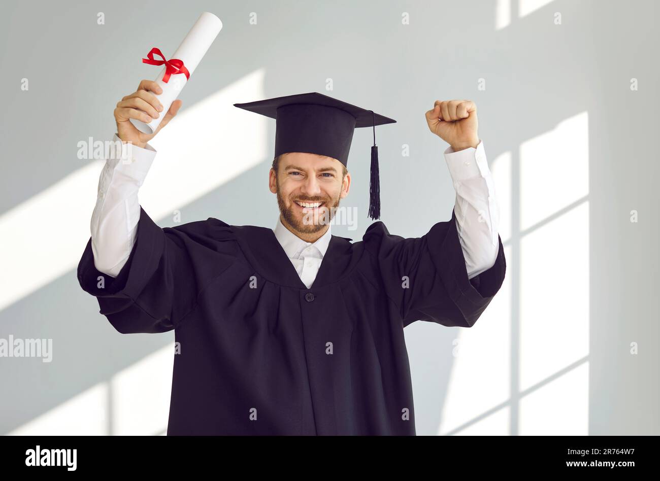 Happy, excited university graduate in cap and gown having fun after ...