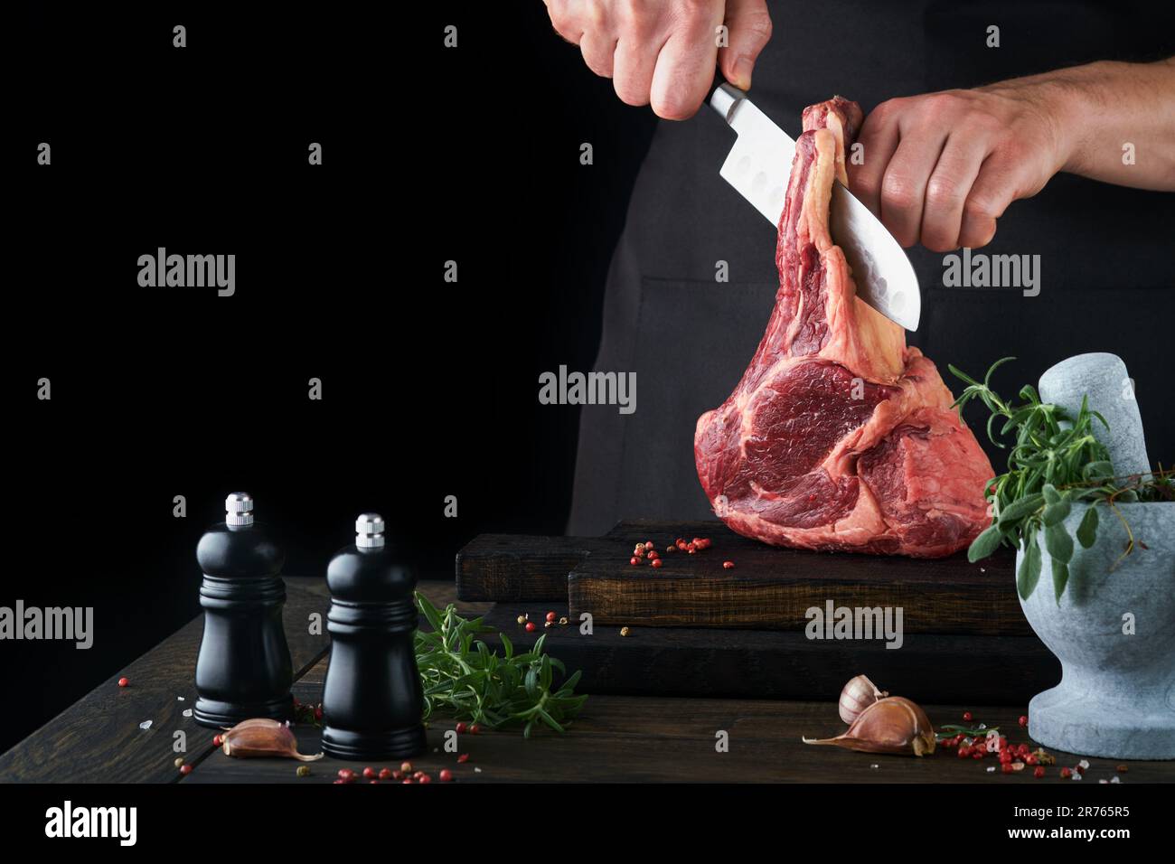 Chef cutting steak beef. Mans hands hold raw steak Tomahawk on rustic ...