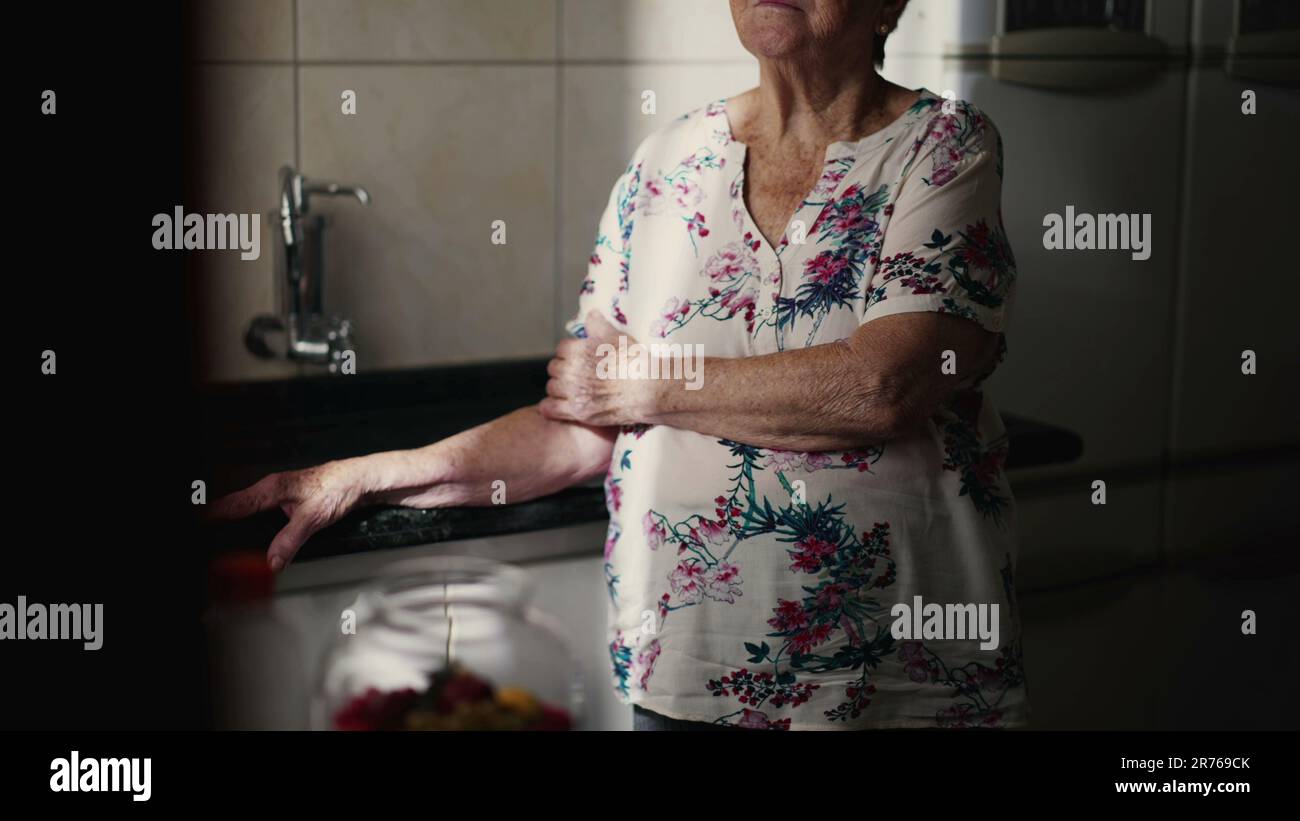 Contemplative senior woman staring out at kitchen window. A caucasian ...