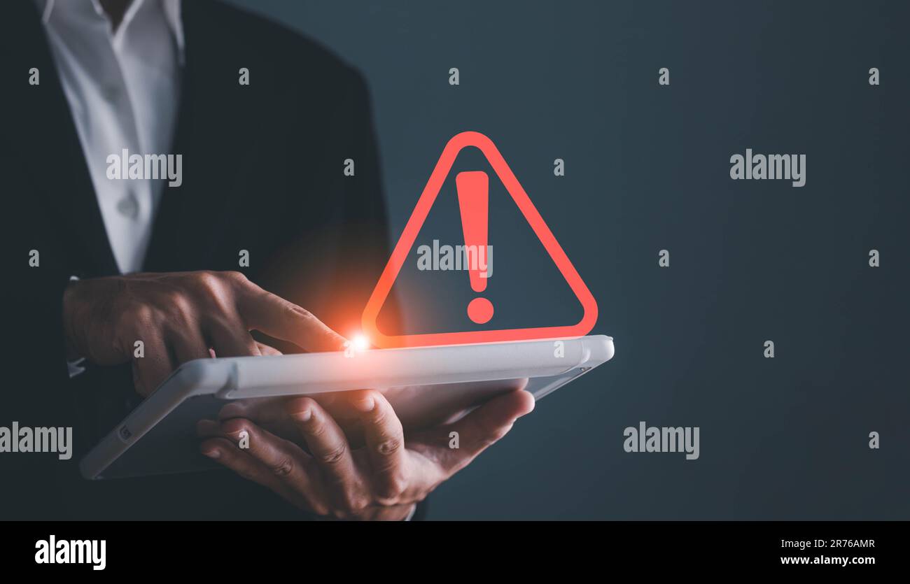 Businessman using tablet with triangle caution warning sing for notification error and ...
