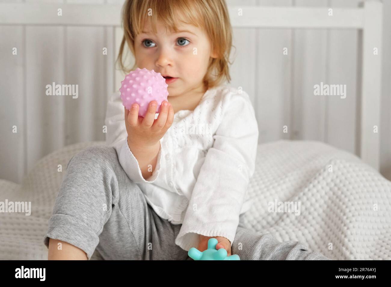 Cute baby girl playing tactile knobby balls. Young child hand plays ...