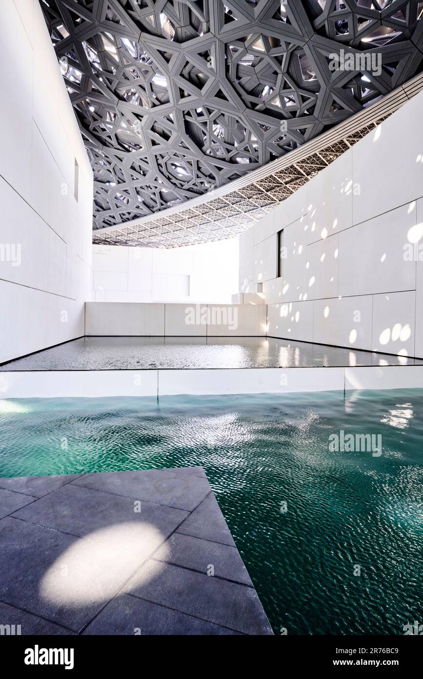 Interior with mesh roof and water feature. Louvre Abu Dhabi, Abu Dhabi ...