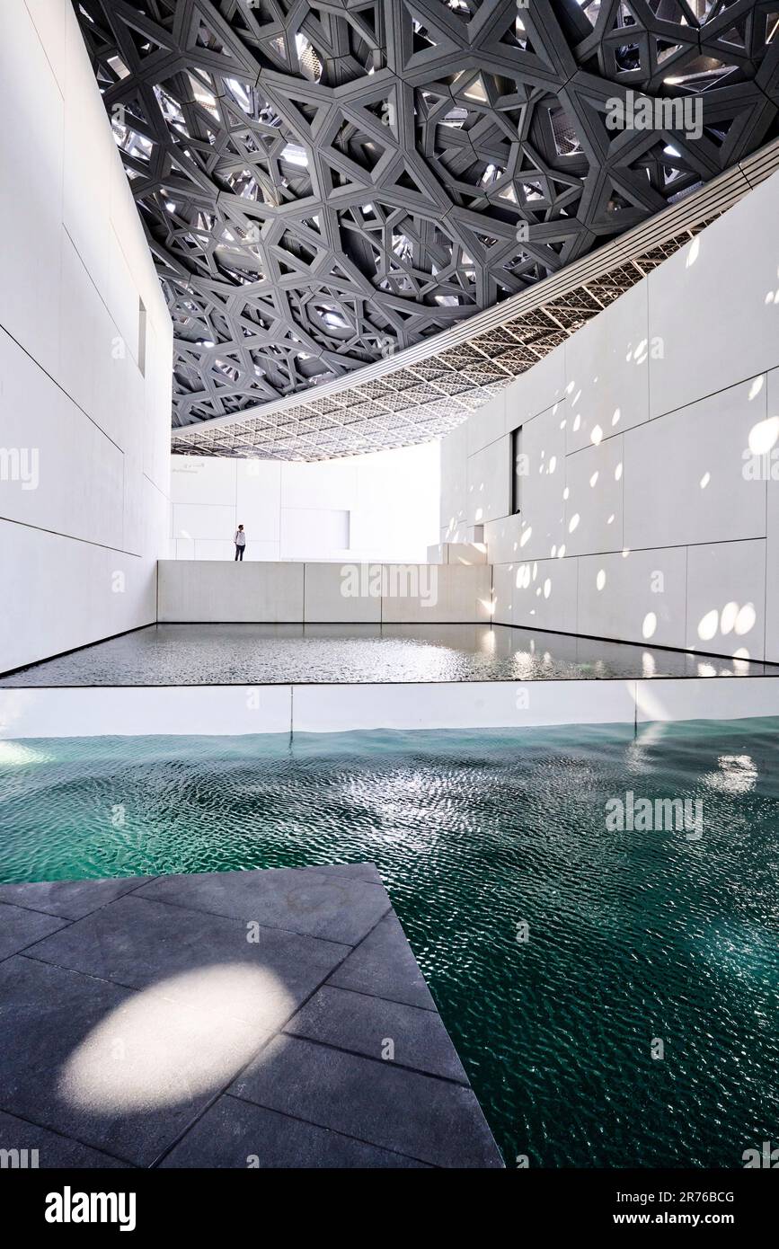 Interior with mesh roof and water feature. Louvre Abu Dhabi, Abu Dhabi ...