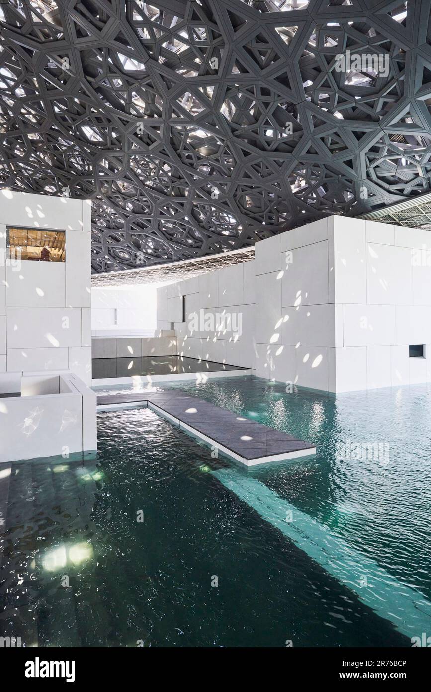 Interior with mesh roof and water feature. Louvre Abu Dhabi, Abu Dhabi ...