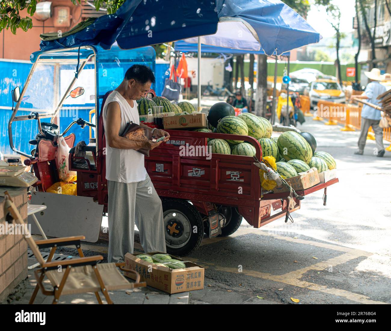 A watermelon vendor counting money outdoors in China Stock Photo - Alamy