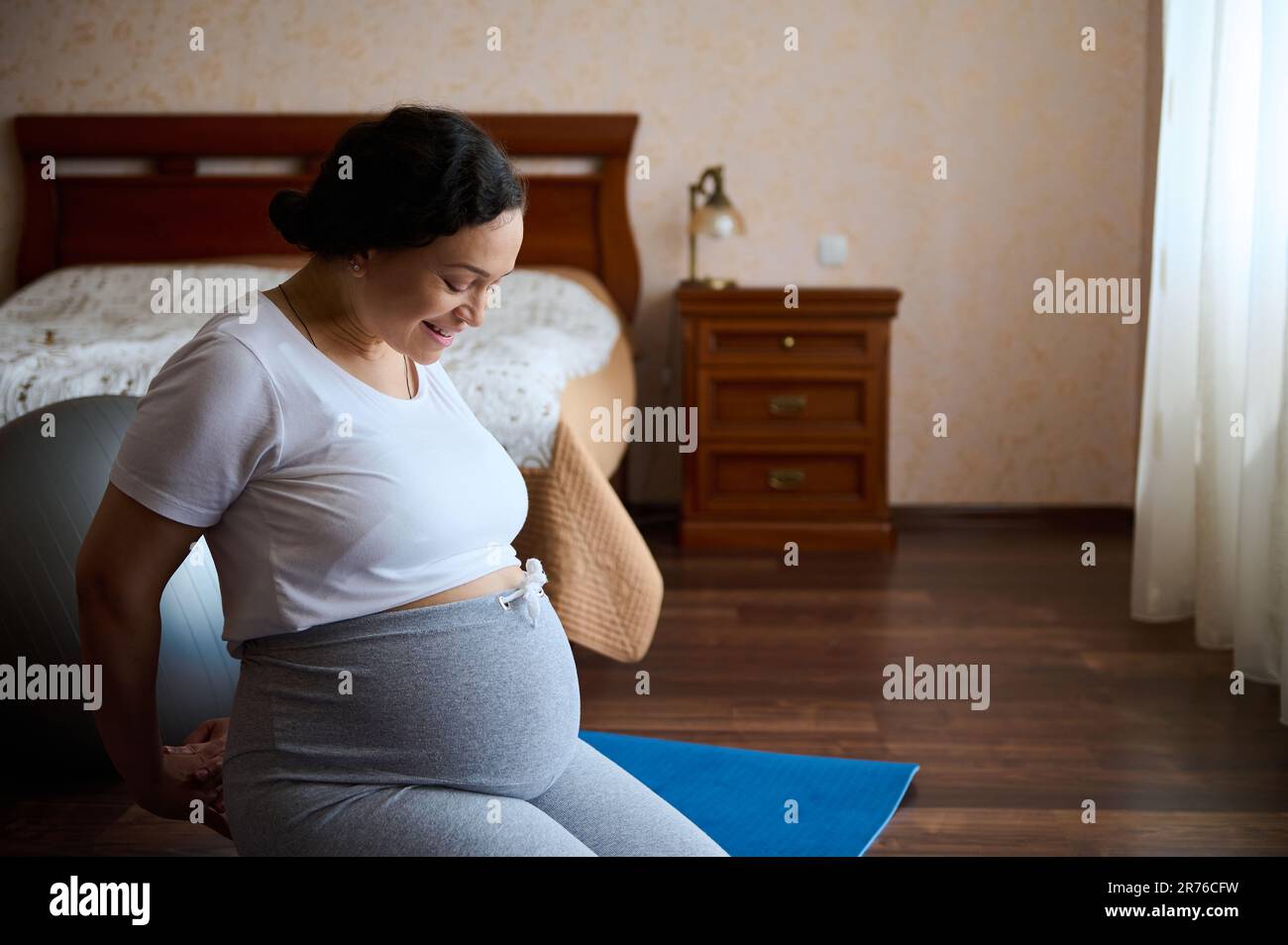 Gravid expectant mother smiling looking at her big belly, feeling ...