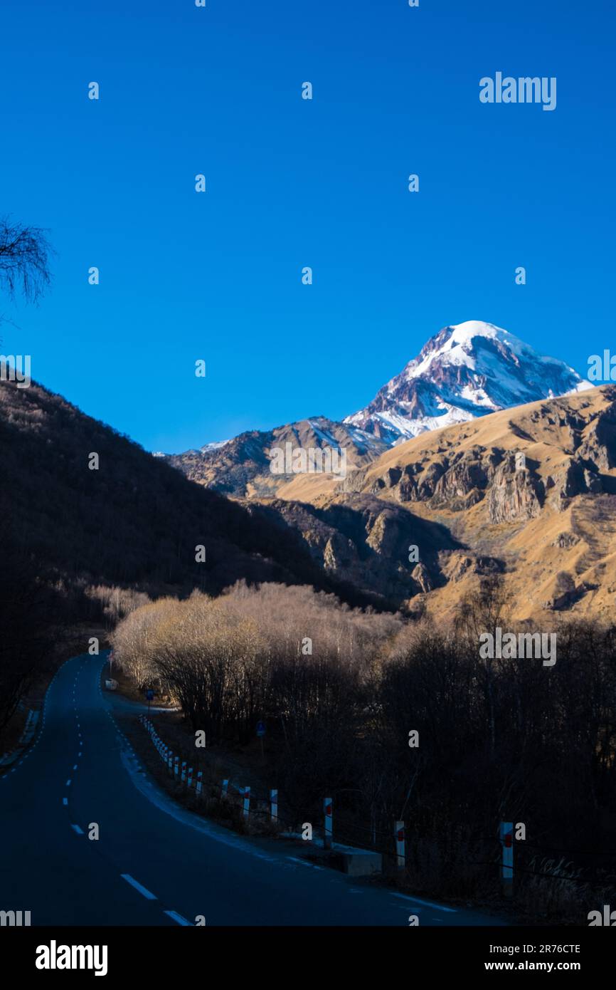 A scenic view of a road leading to the majestic Kazbegi mountain in the ...