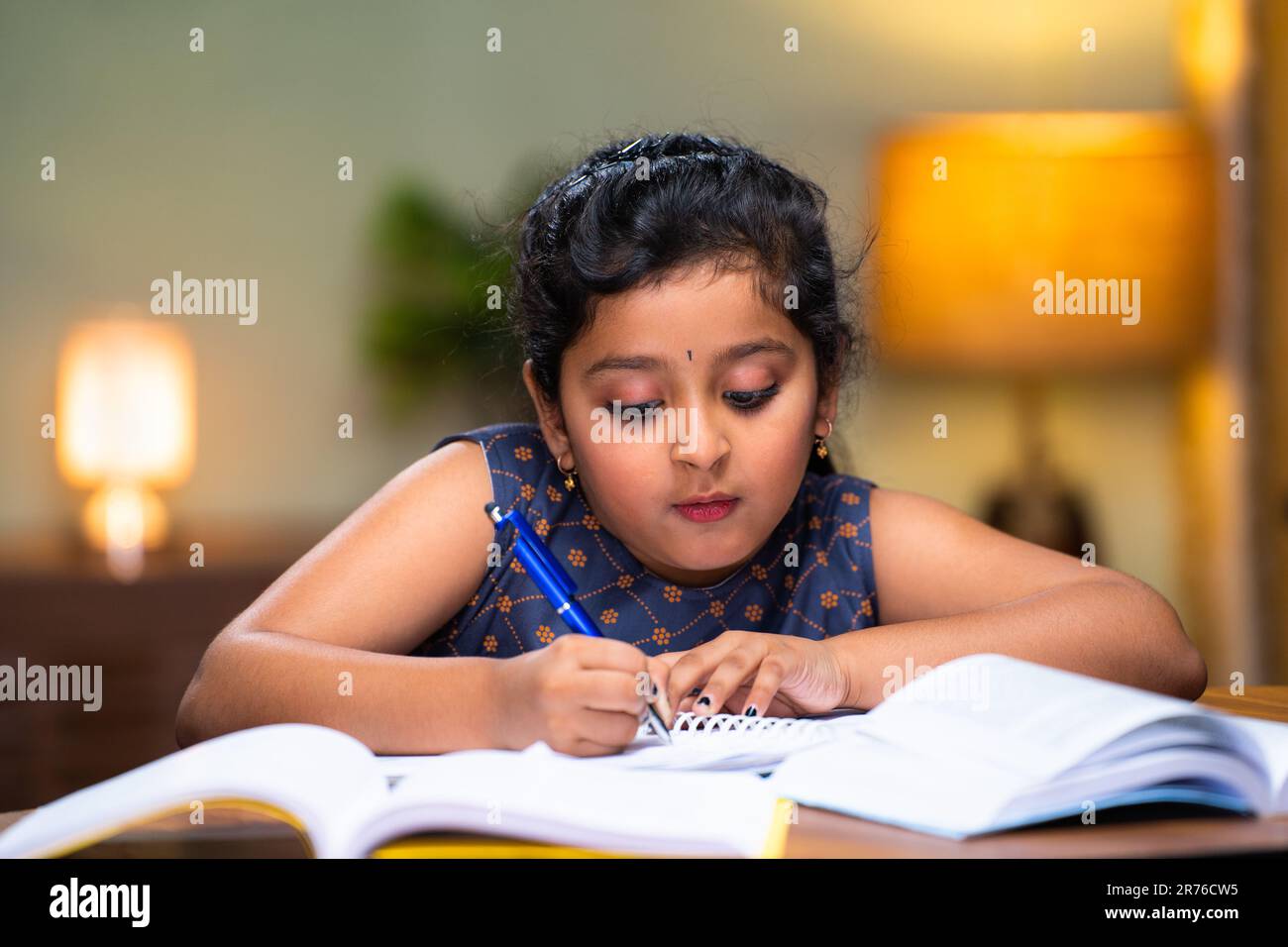 Indian young girl kid writing notes on book at home - concept of ...