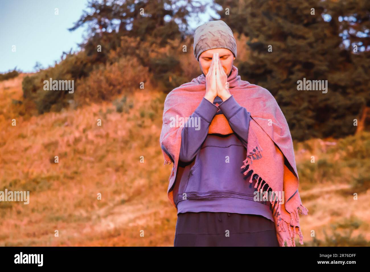 Man in shawl with namaste hands praying in mountains. Sunrise praying ...