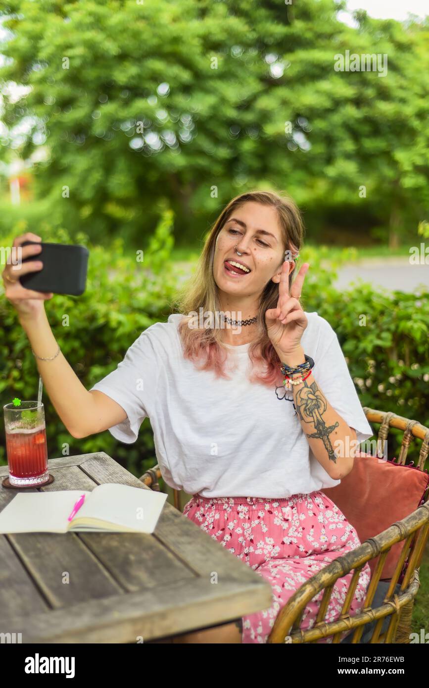 Cute woman taking a photo selfie and drinking tea in summer garden ...