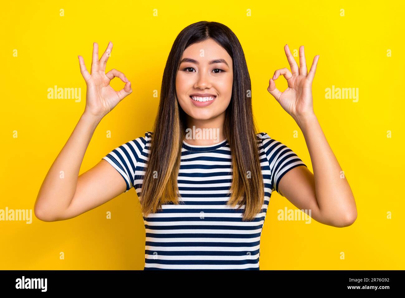 Closeup portrait of young charming japanese woman showing okey sign recommendation double symbol ...