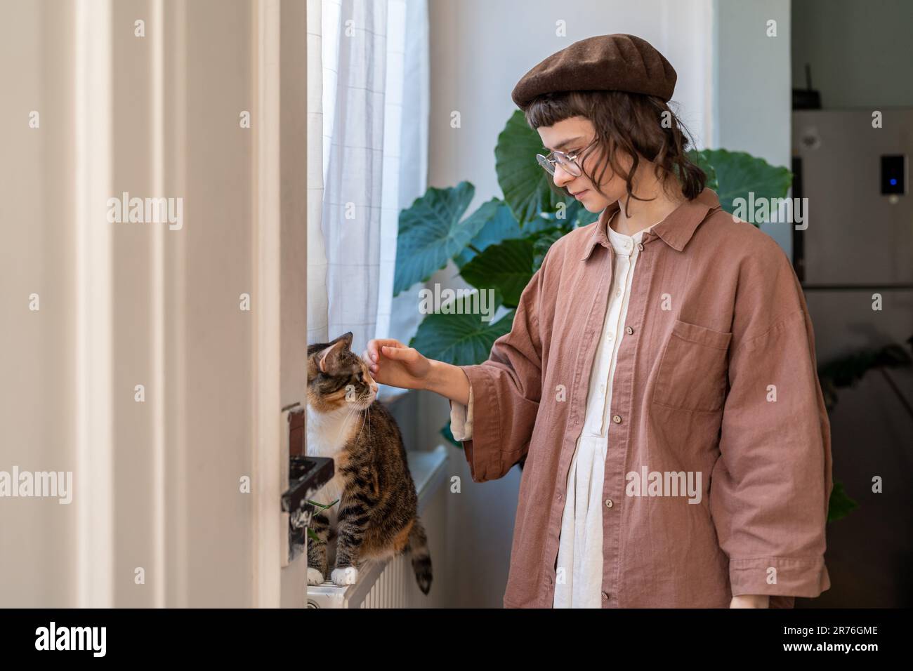 Millennial girl petting fuzzy cat sitting on windowsill Stock Photo - Alamy