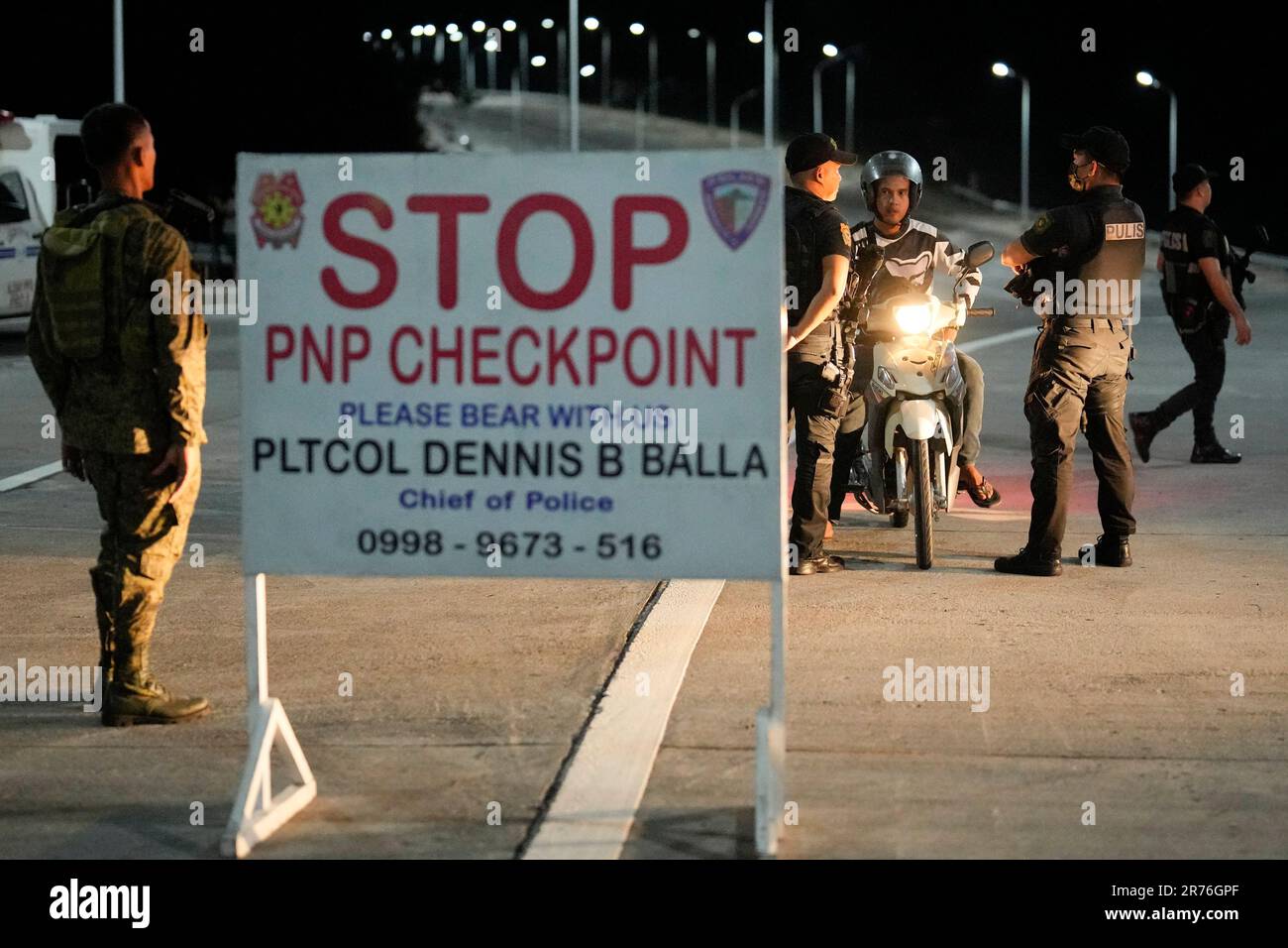 Police stop a motorcycle rider at a checkpoint at the border of the ...