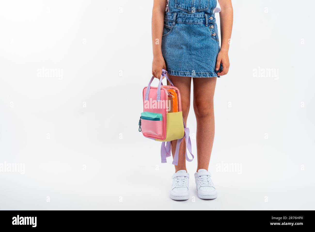 Crop anonymous girl in denim shorts and sneakers standing on white ...