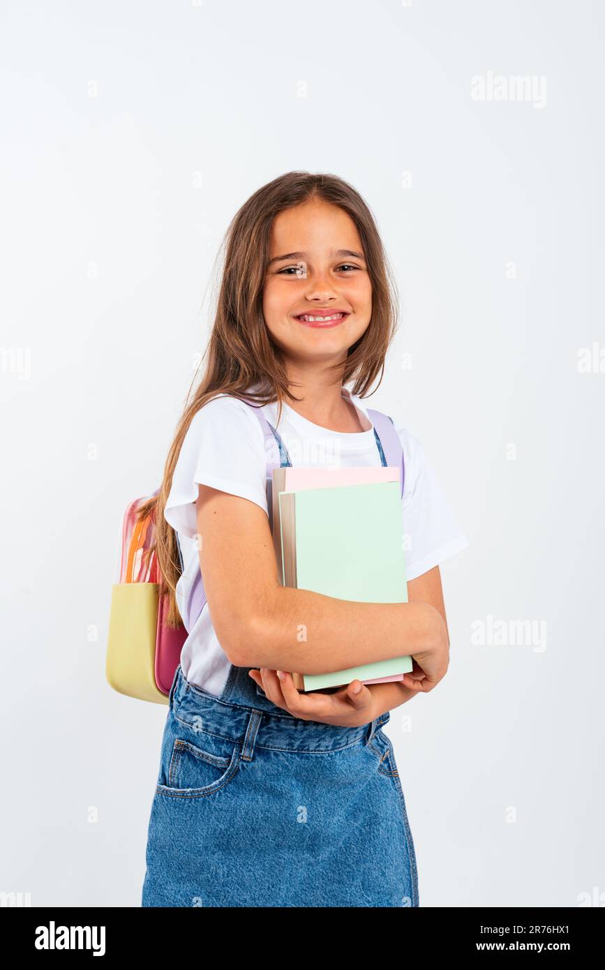 Positive little girl in denim overall smiling and looking at camera ...