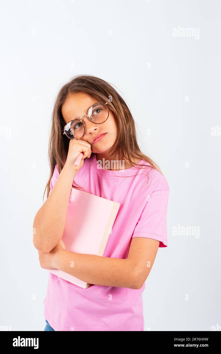 Thoughtful teen girl in casual clothes and eyeglasses touching face ...