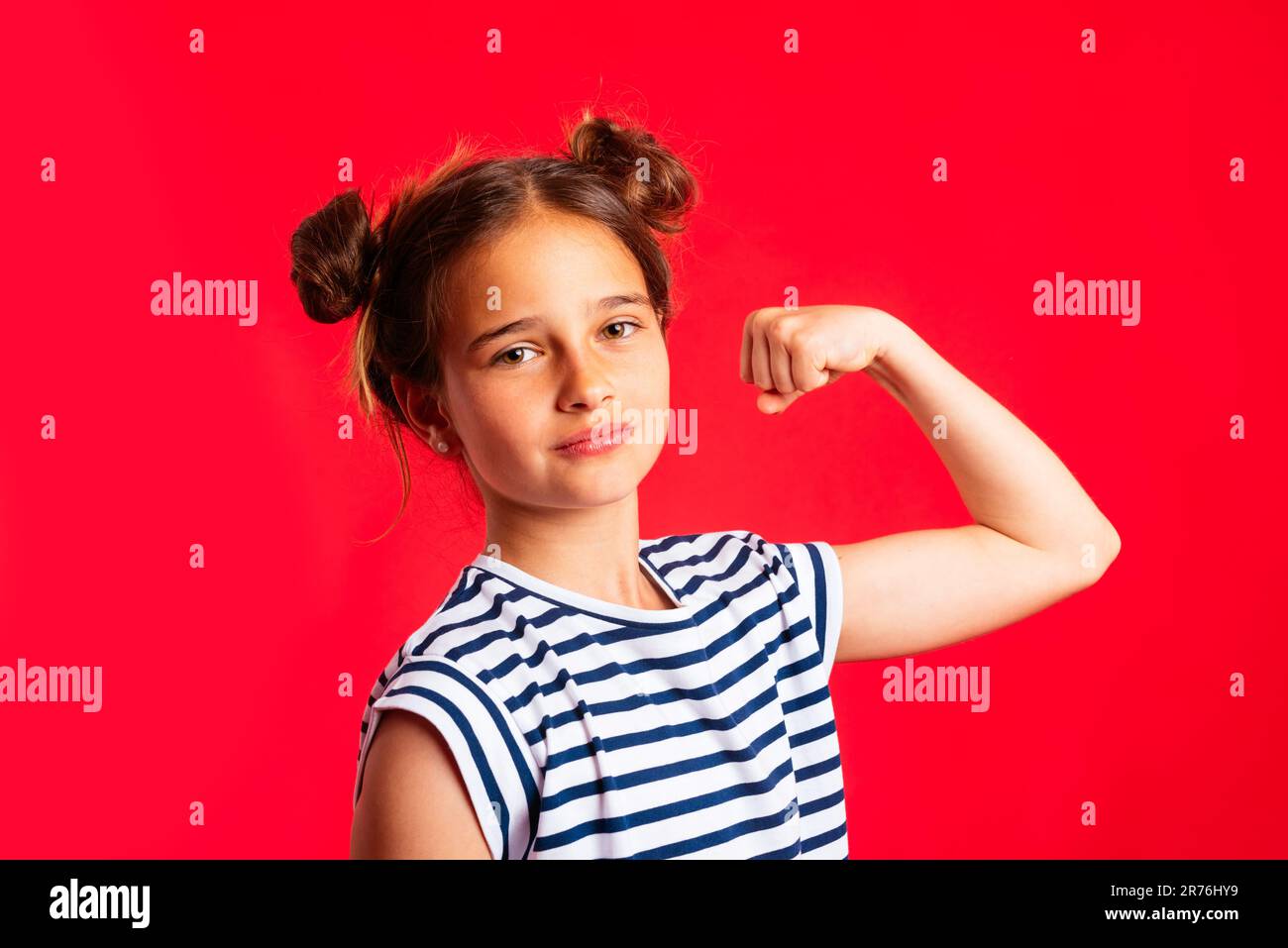 Portrait of adorable girl in striped shirt looking at camera while ...